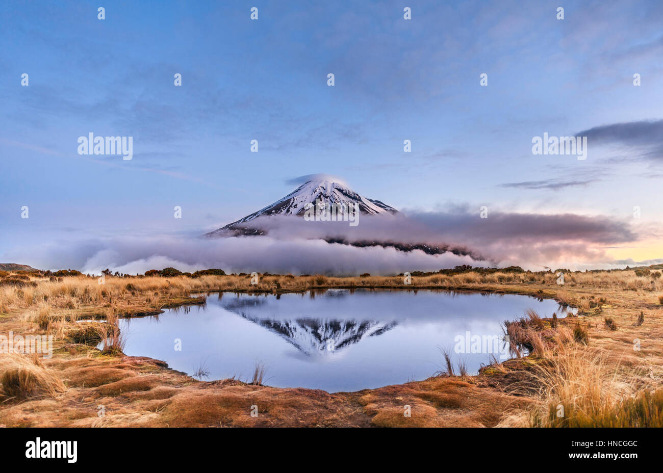 Reflection in Pouakai Tarn lake, clouds around stratovolcano Mount ...