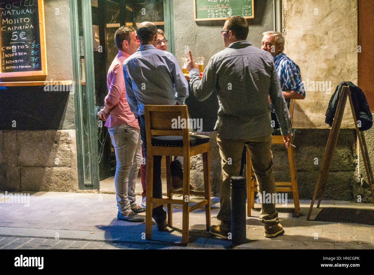 Spanish men drinking and talking at an outside table at a taverna in ...