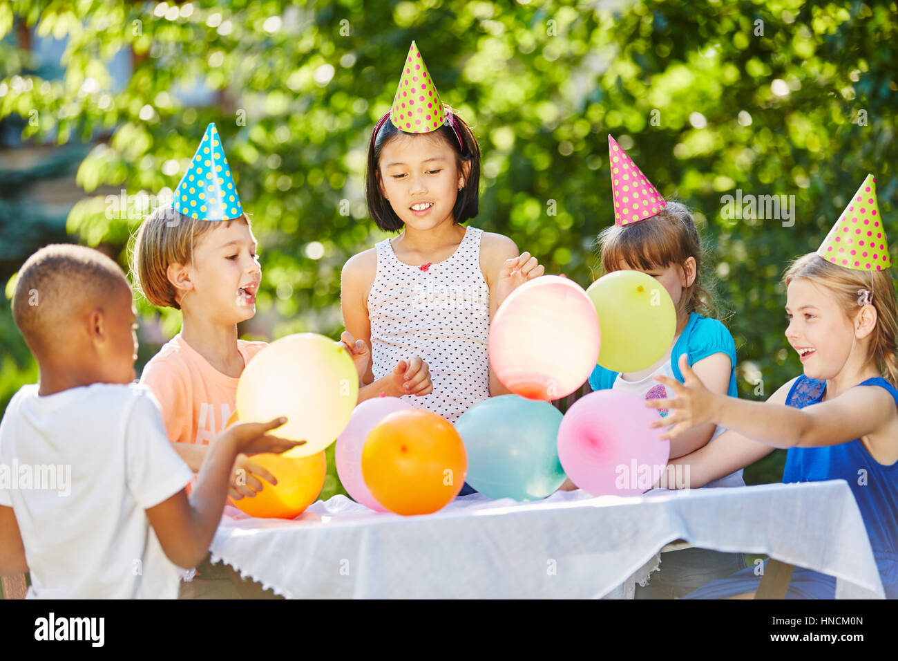 Many kids celebrate birthday together with balloons and party hats ...