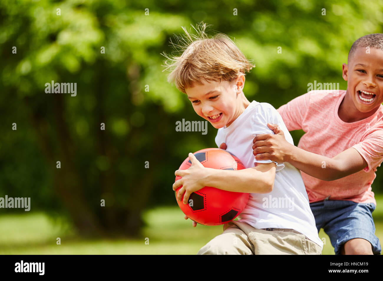 Two children having fun in summer playing with soccer ball as friends ...