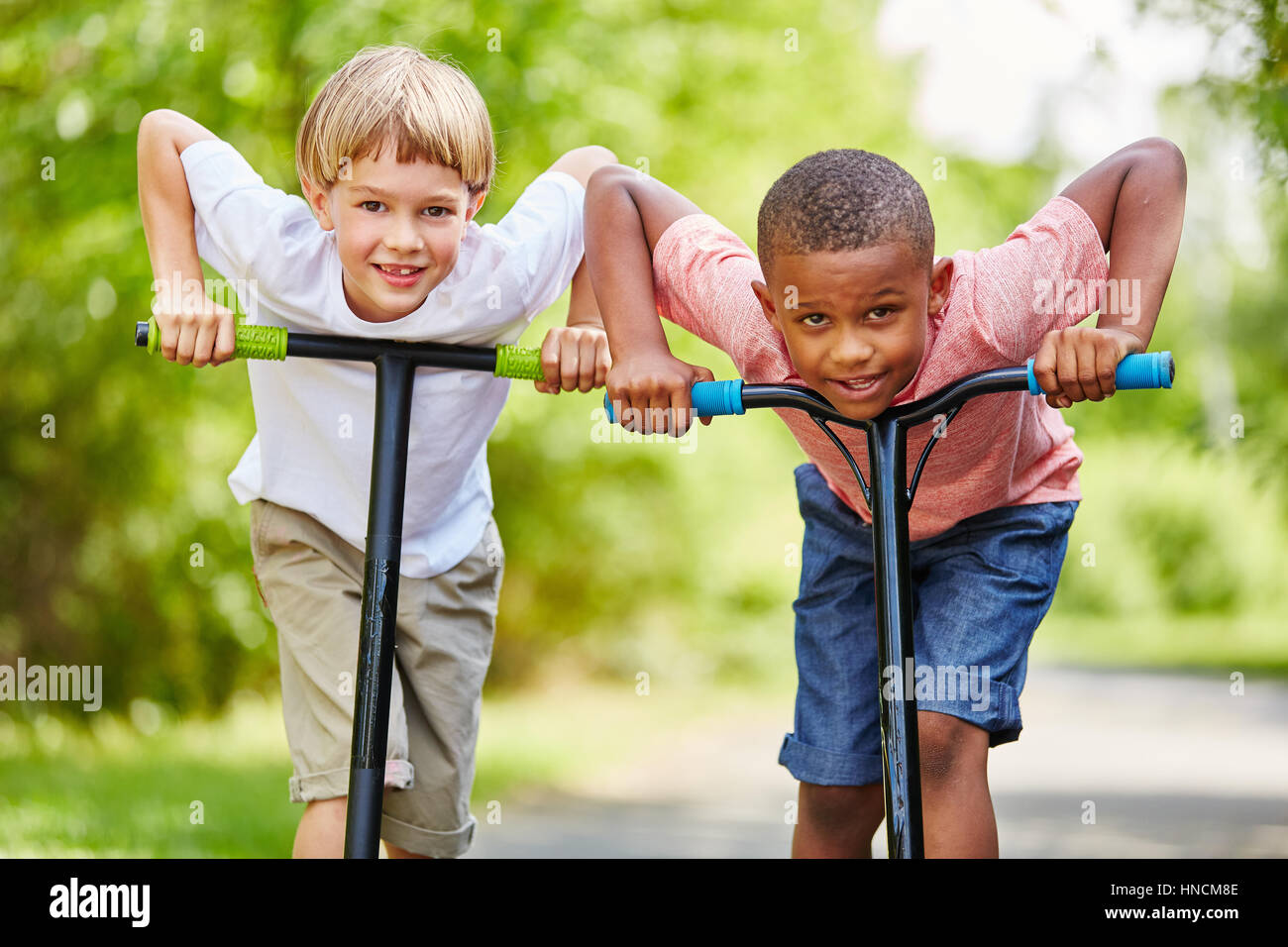 Two boys excited about race with scooters in the park Stock Photo - Alamy