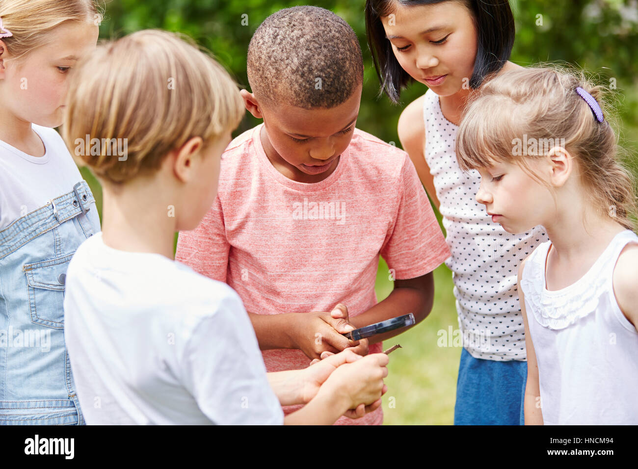 Children researching about nature in teamwork with magnifying glass ...