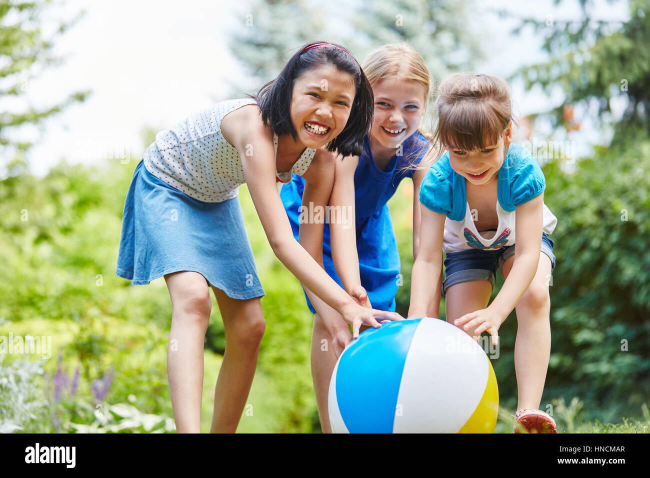 Three girls as friends roll ball in teamwork and have fun in summer ...