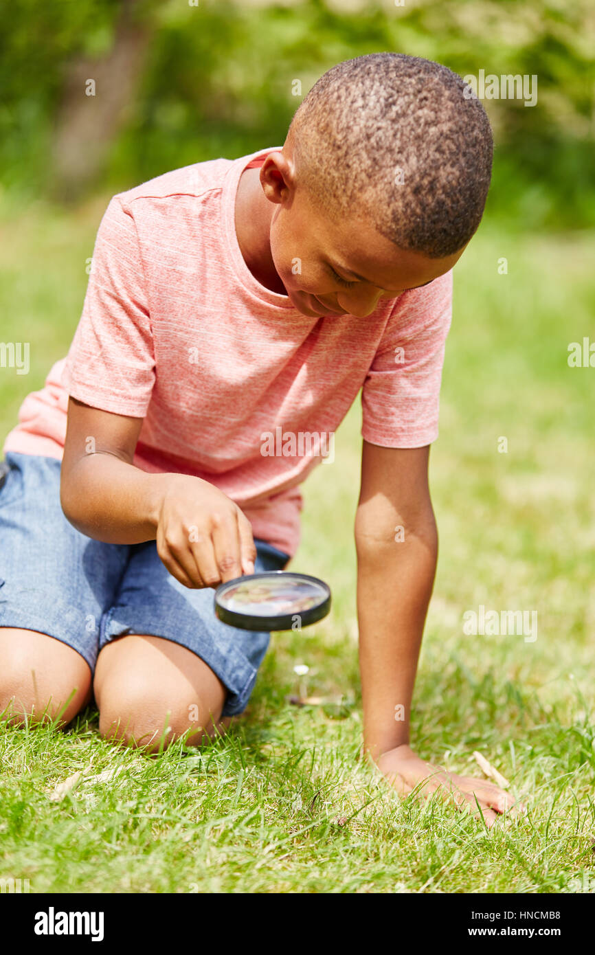 Boy as detective with loupe exploring nature with curiosity Stock Photo ...