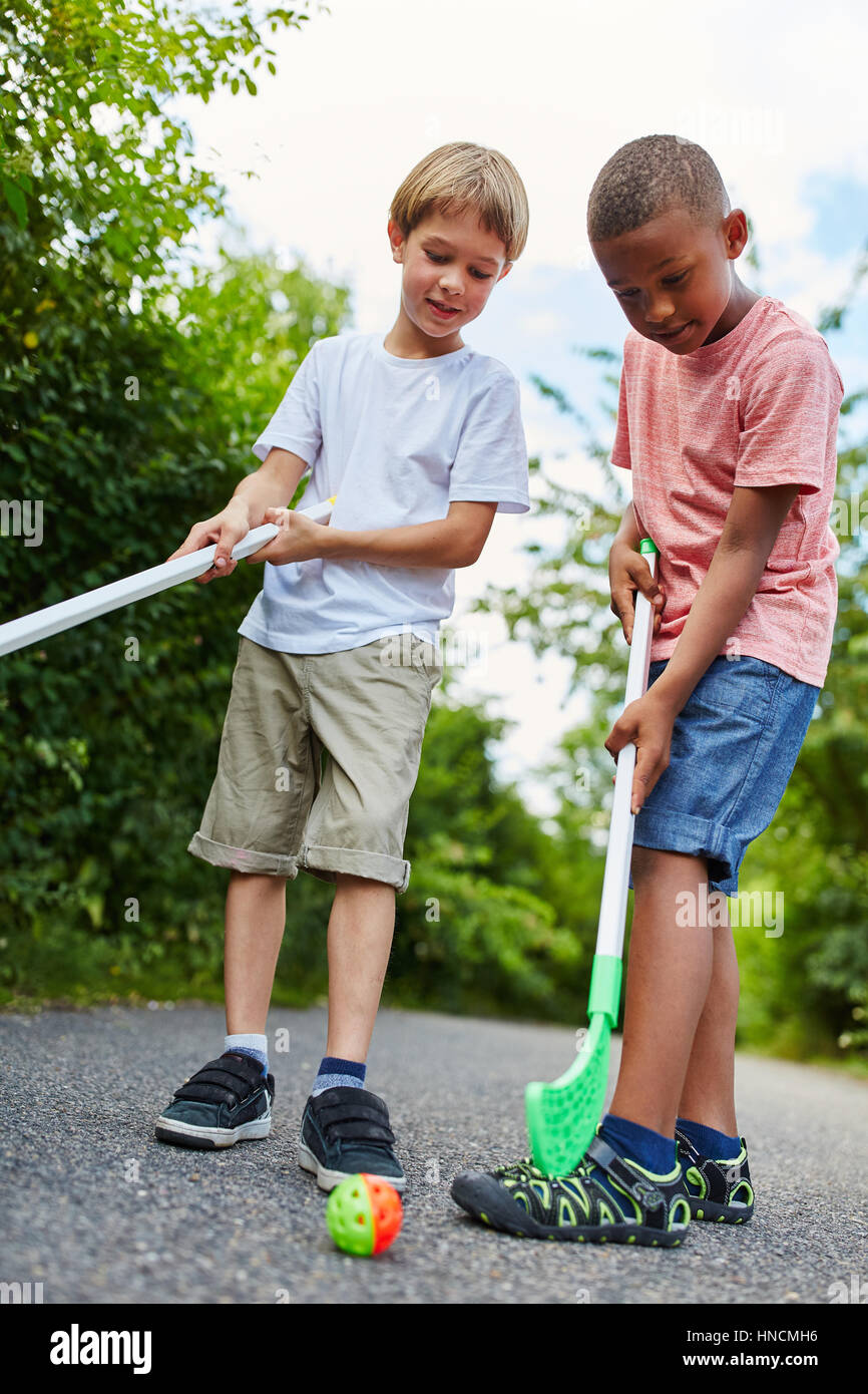 Two kids play together street hockey as friends Stock Photo - Alamy