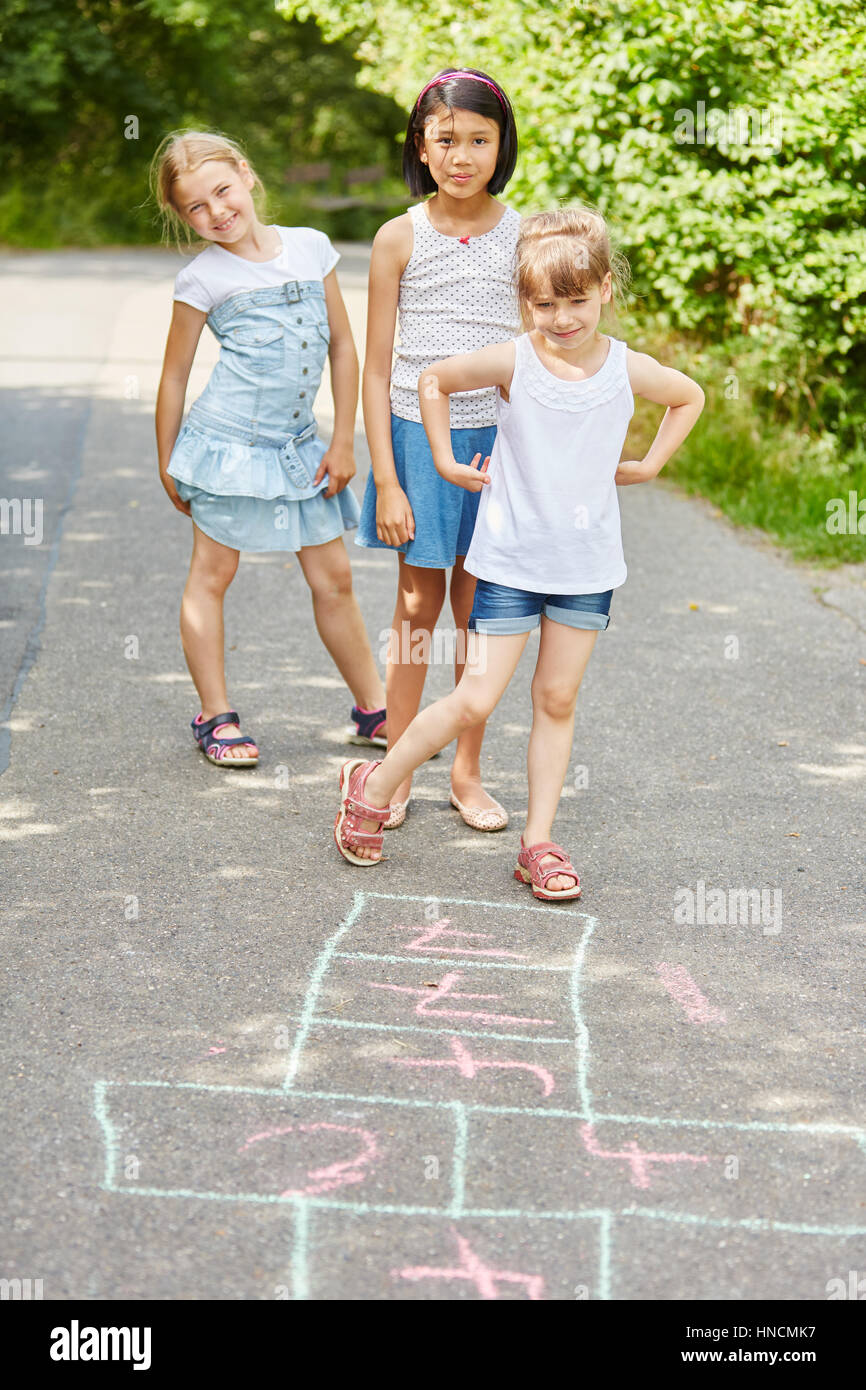 Three girls as friends play hopscotch at the park Stock Photo - Alamy