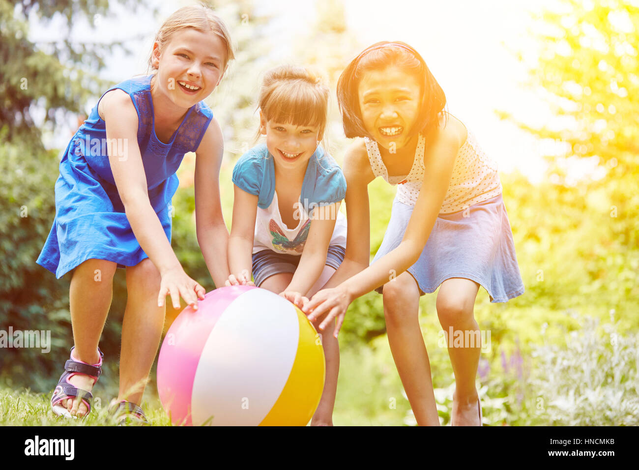 Three happy girls roll ball in summer in garden Stock Photo - Alamy