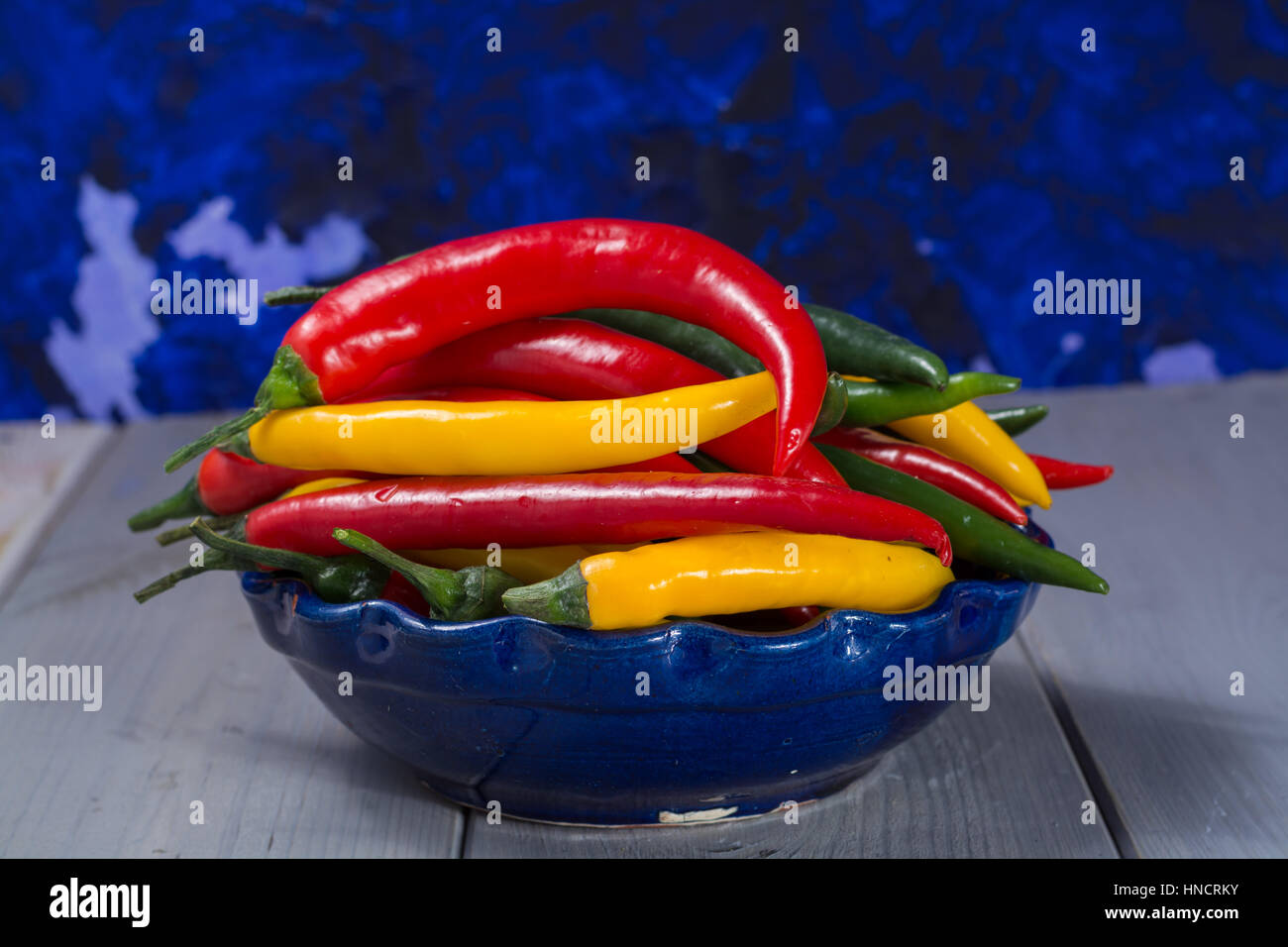 Red, green and yellow mexican hot chili peppers on blue background in ...