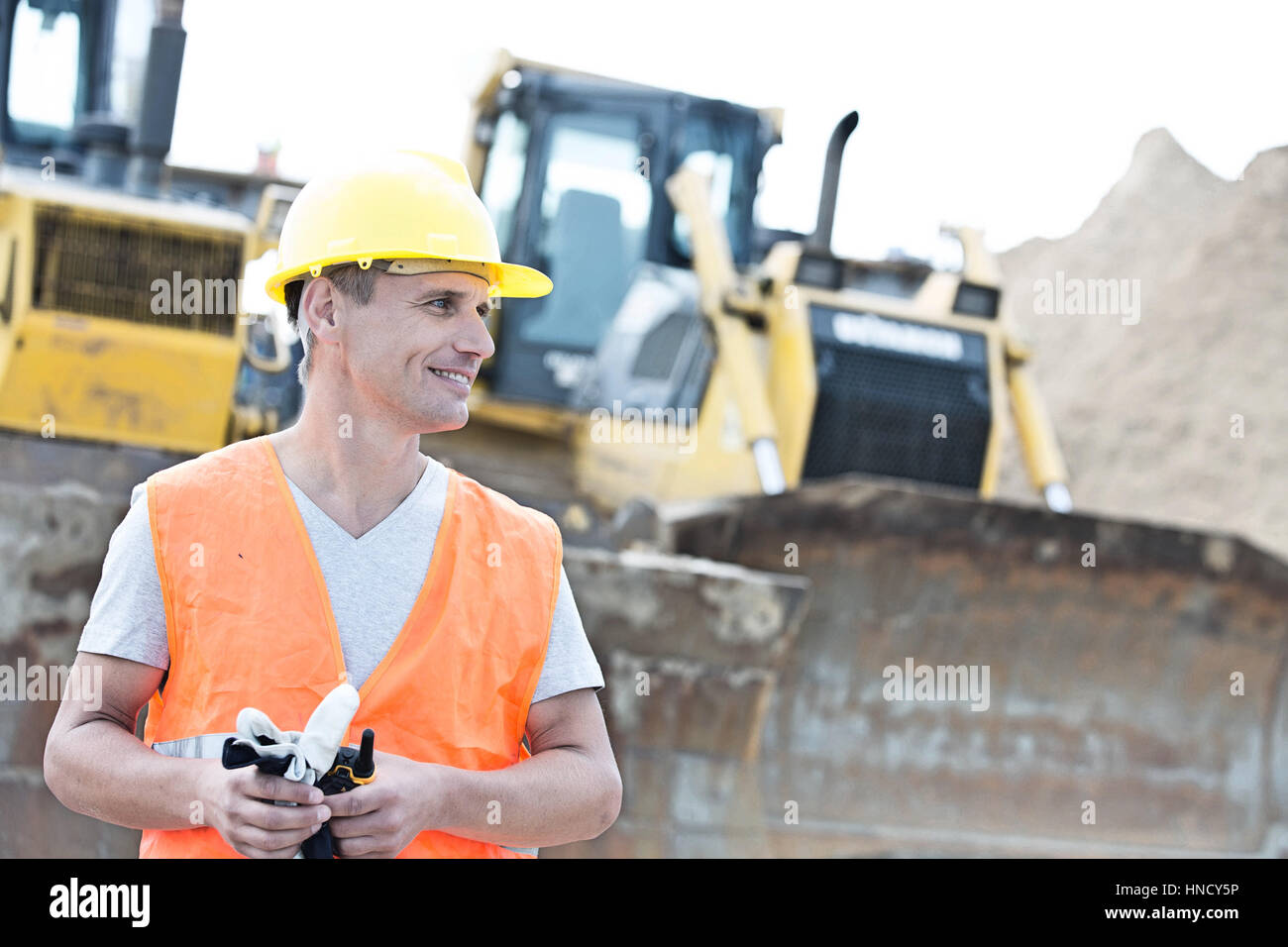 Smiling supervisor looking away at construction site Stock Photo - Alamy