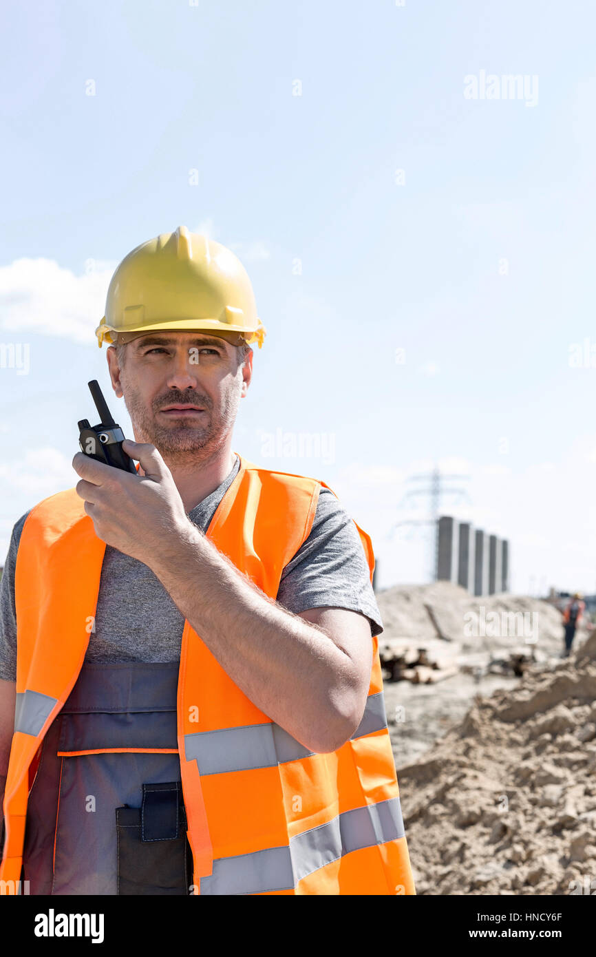 Confident supervisor using walkie-talkie at construction site against ...