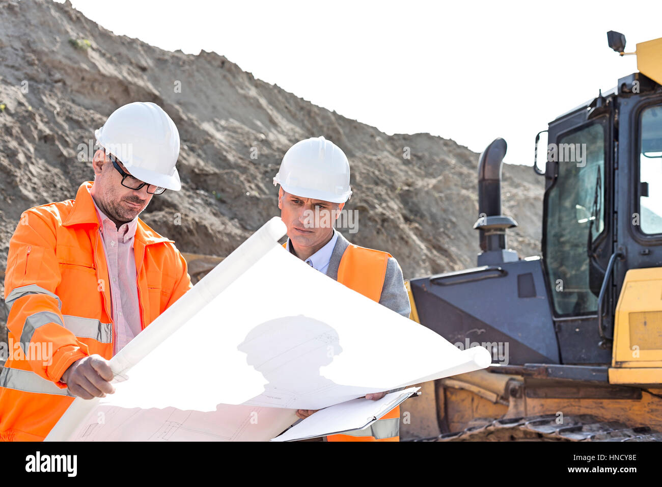 Engineers analyzing blueprint at construction site Stock Photo - Alamy