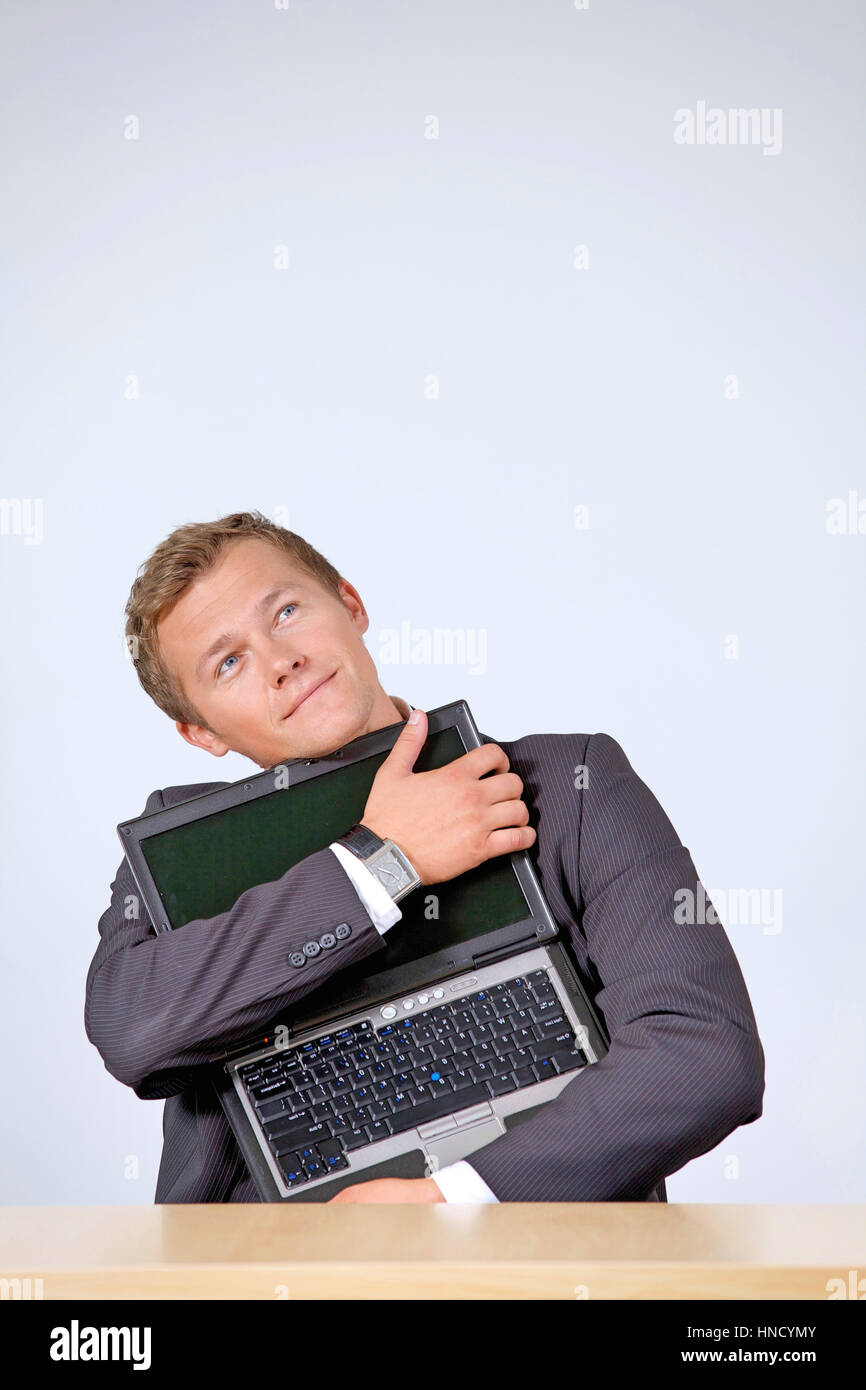 Businessman embracing laptop, looking up Stock Photo - Alamy