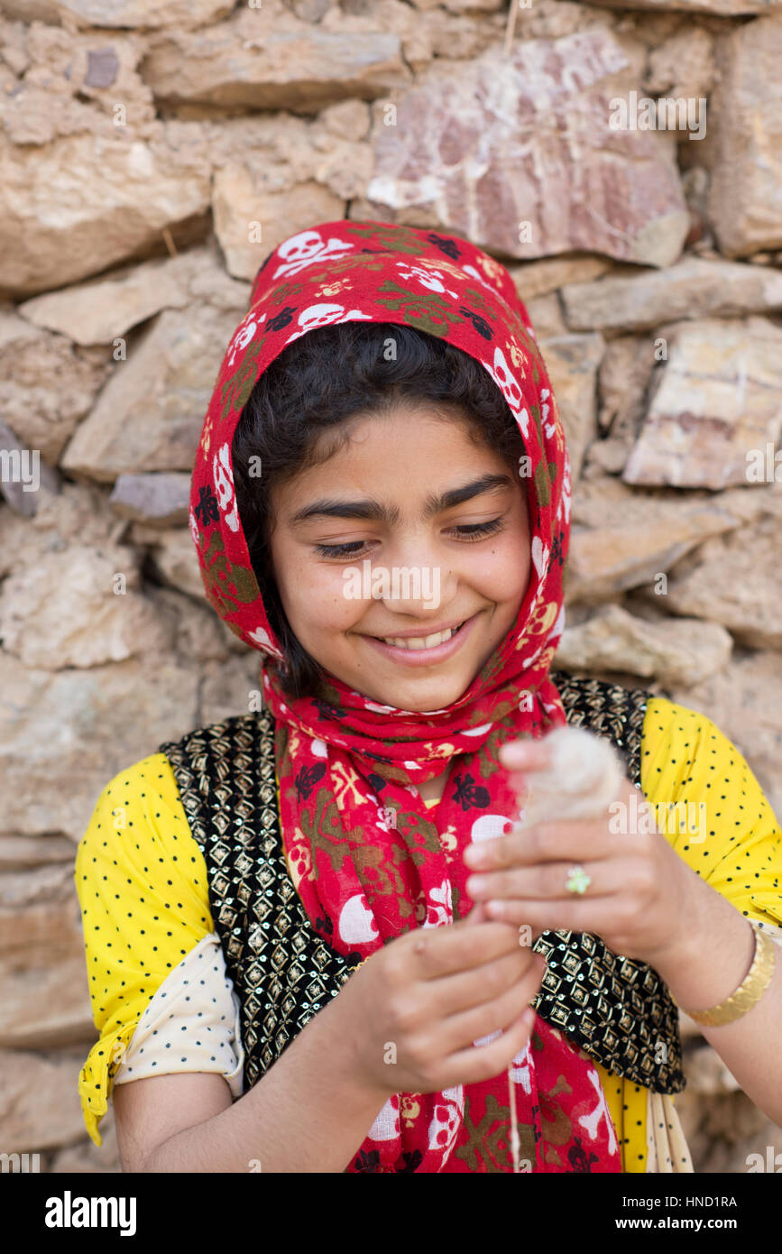 A young kurdish girl with red veil carding wool, Palangan ancient village, Iranian Kurdistan ...