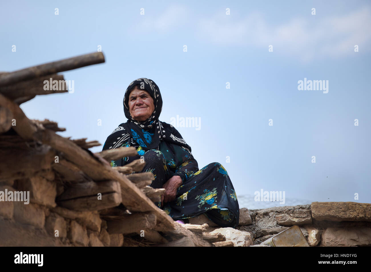 An old kurdish woman seated on the roof of a traditional house, Palangan ancient village ...