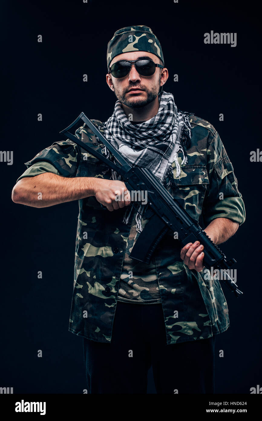 Portrait of a heavily armed masked soldier with black background ...