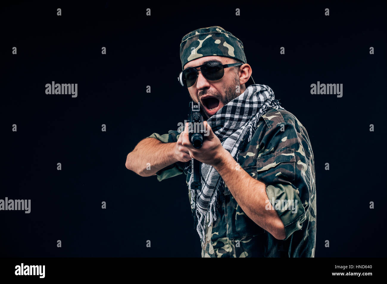 Terrorist atack. Portrait of Terrorist with gun and sunglases over dark ...