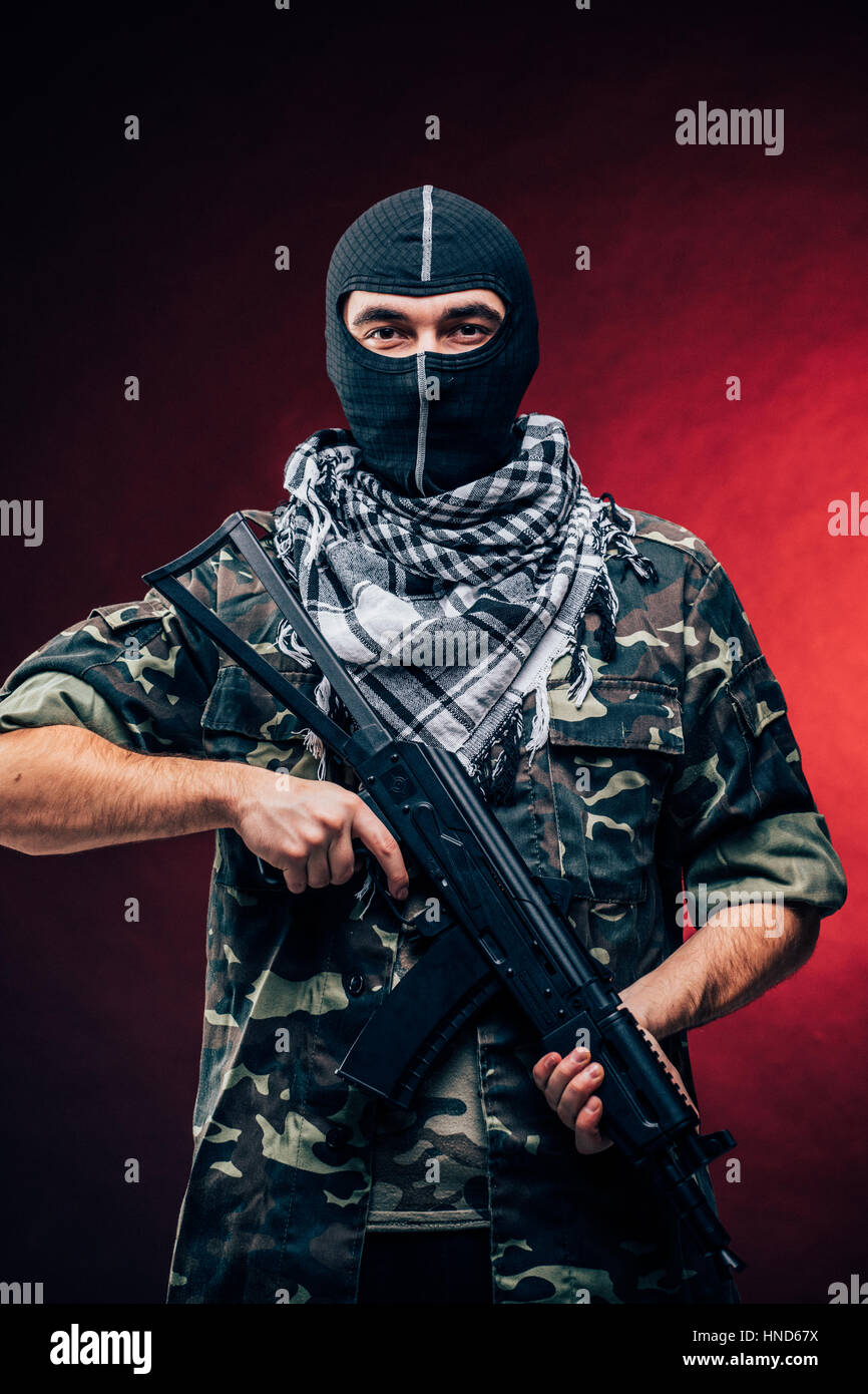Terrorist with weapon aim on red background Stock Photo - Alamy
