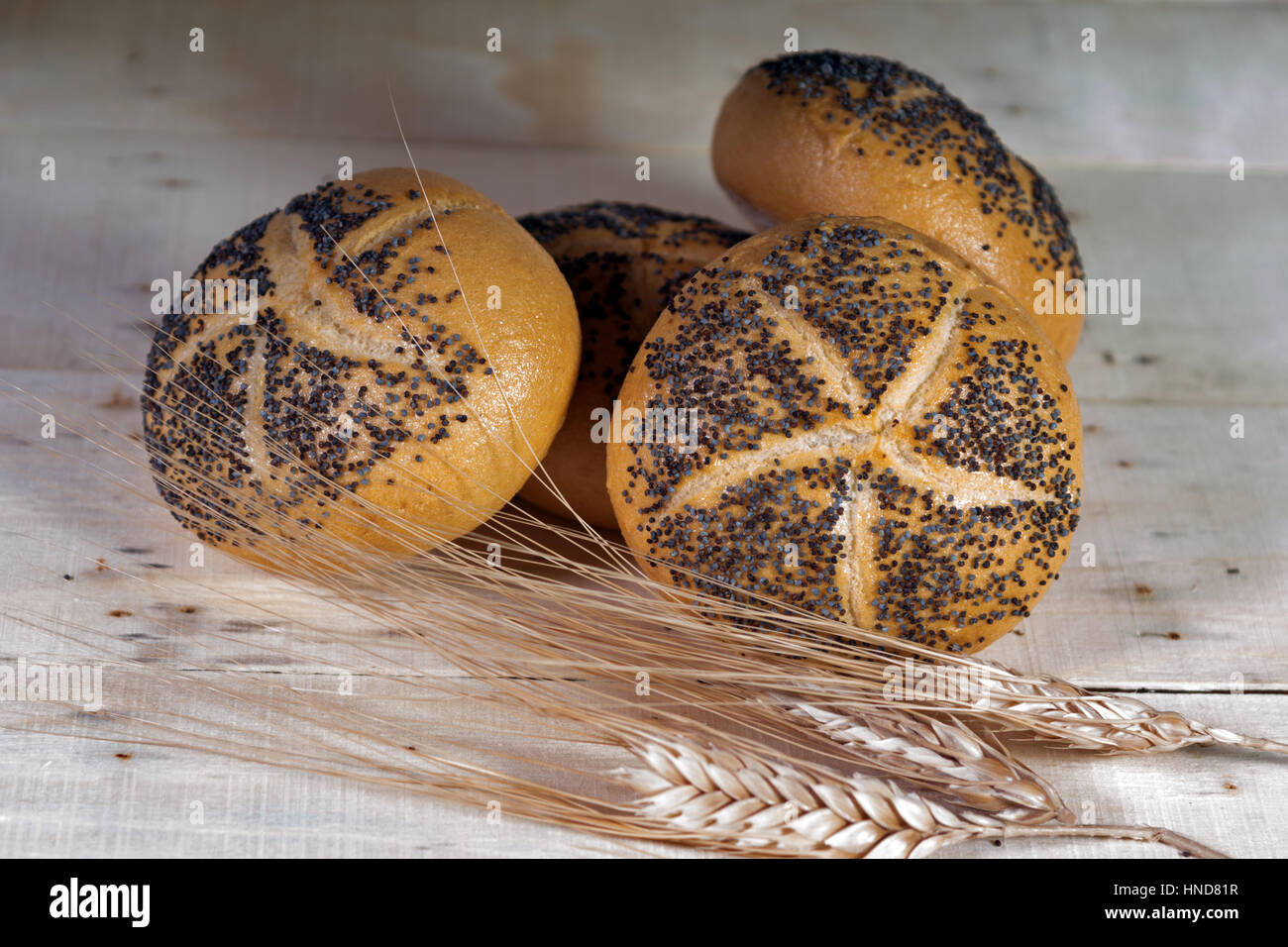 Small bread with poppy seeds and Wheat on wooden background Stock Photo ...