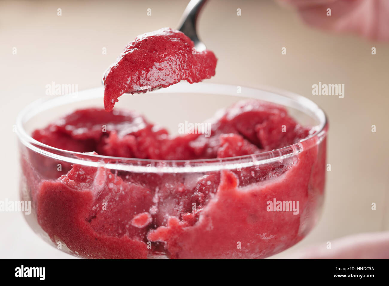 eating raspberry sorbet ice cream with spoon closeup, shallow focus ...