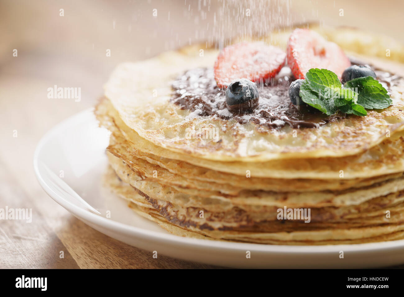 fresh blinis or crepes with melted dark chocolate, berries and sugar ...