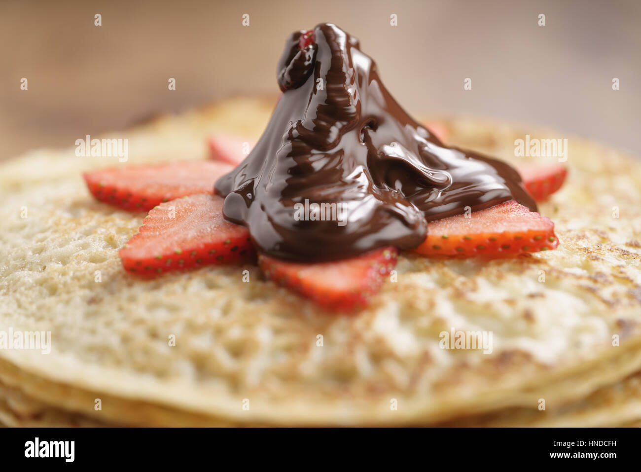 premium dark chocolate poured on blinis with strawberry, shallow focus ...