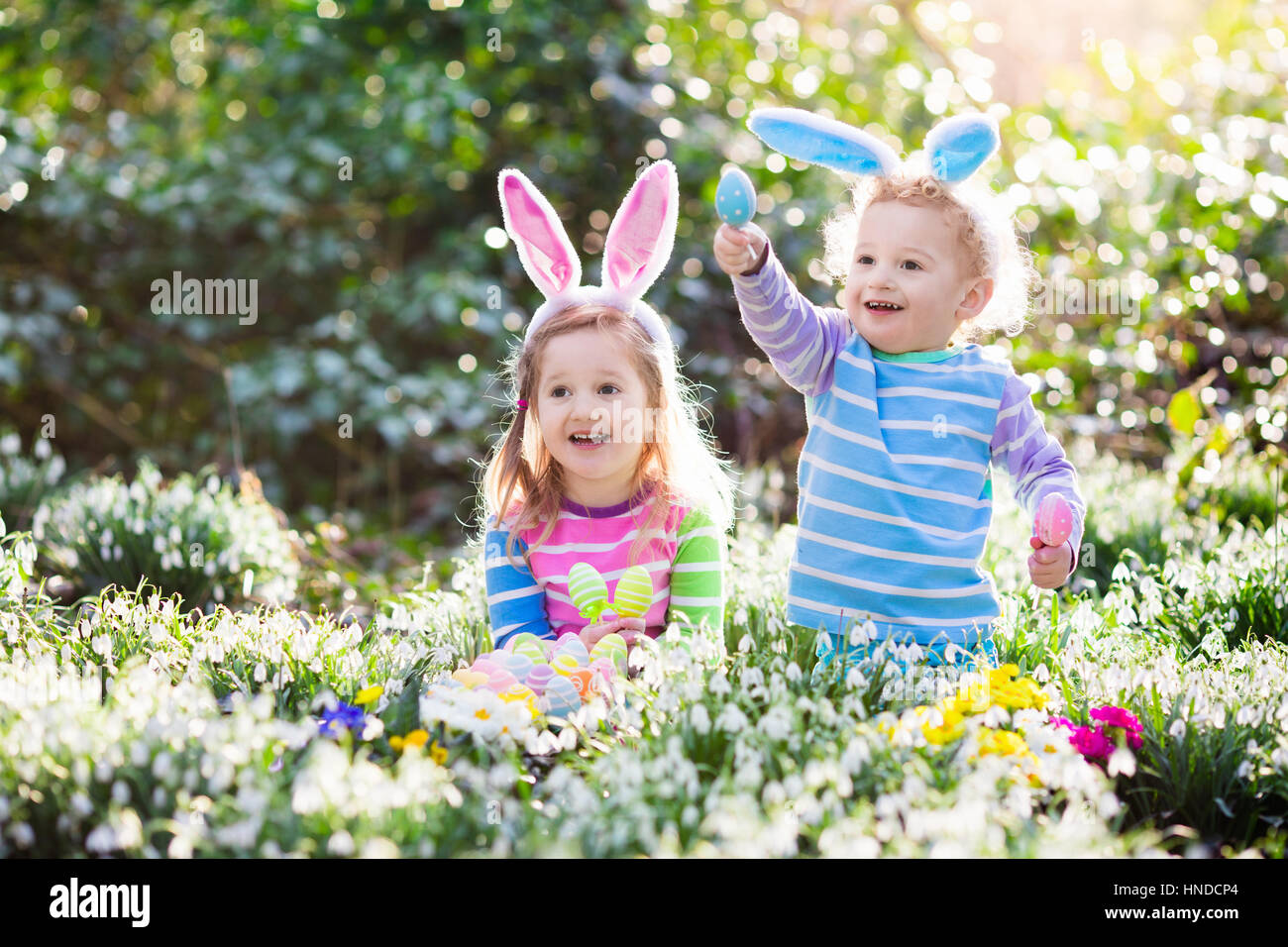 Kids on Easter egg hunt in blooming spring garden. Children with bunny ...
