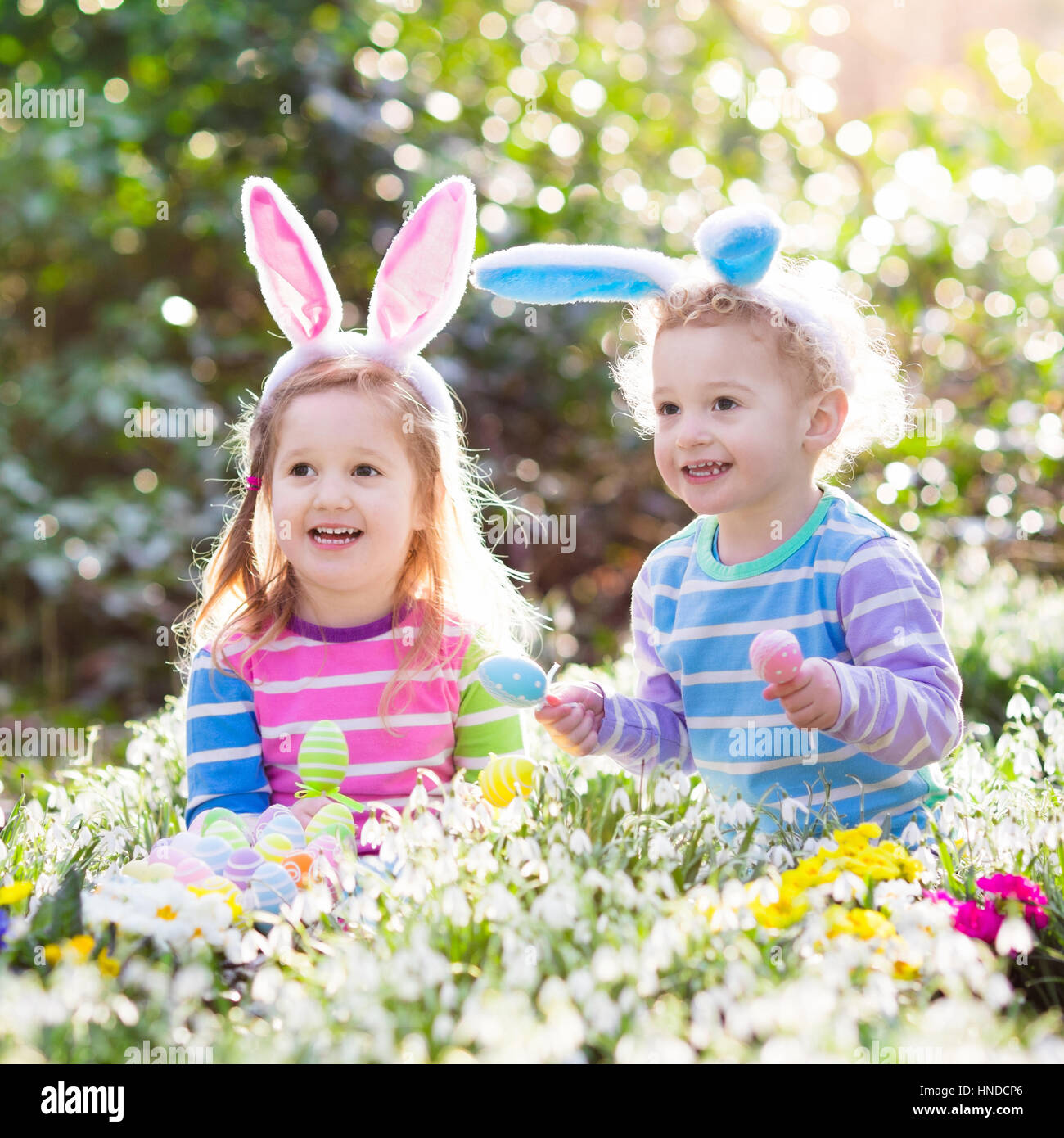 Kids on Easter egg hunt in blooming spring garden. Children with bunny ...