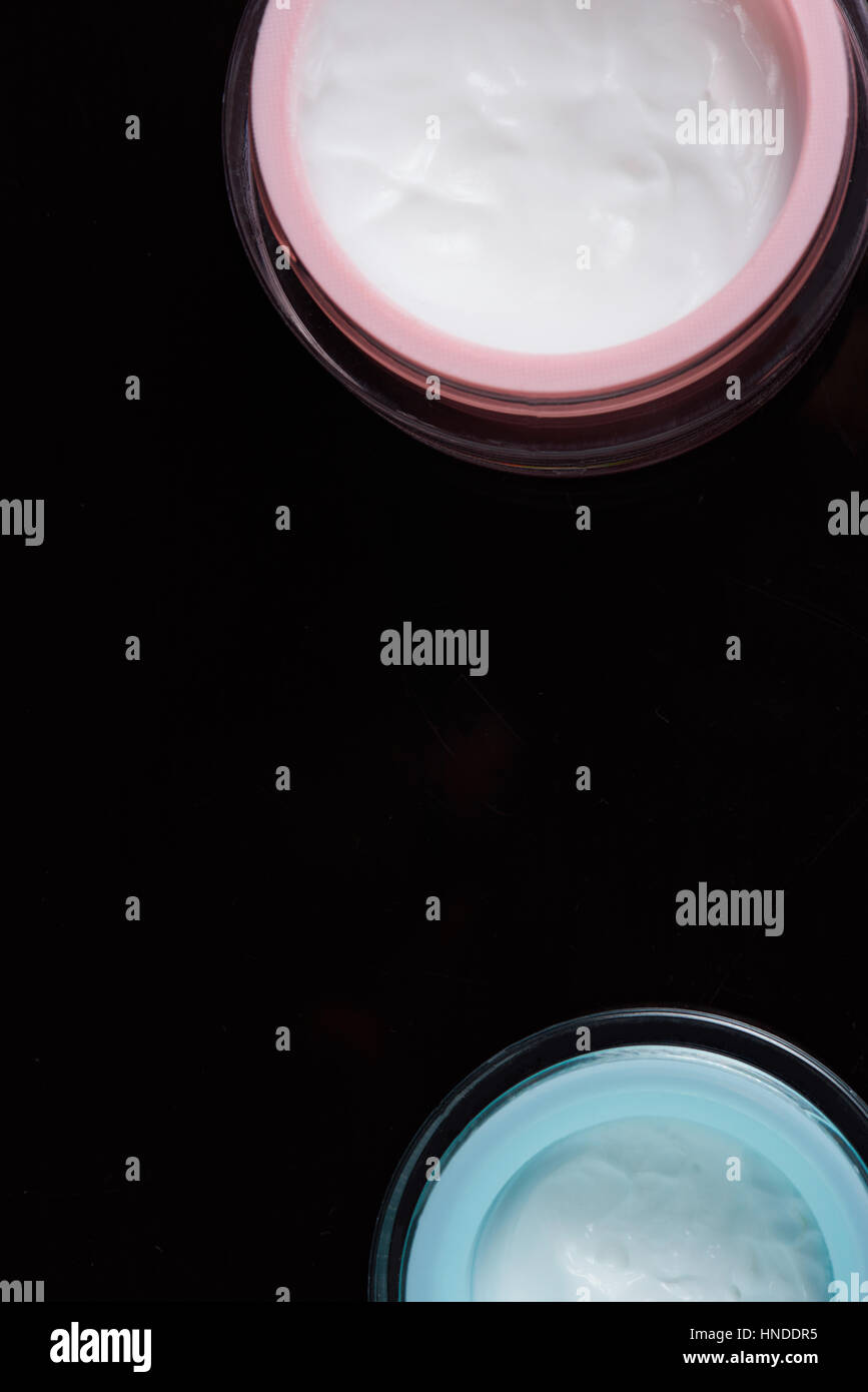 Close up of cream face jars vertical isolated on black background view ...