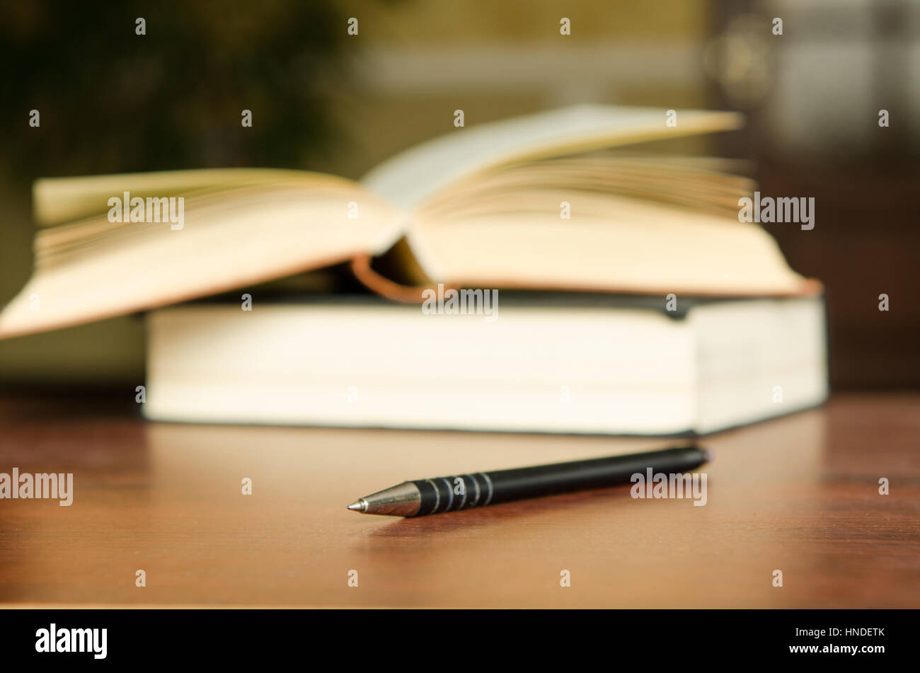pen on background of a stack of colorful books in a library or a room ...