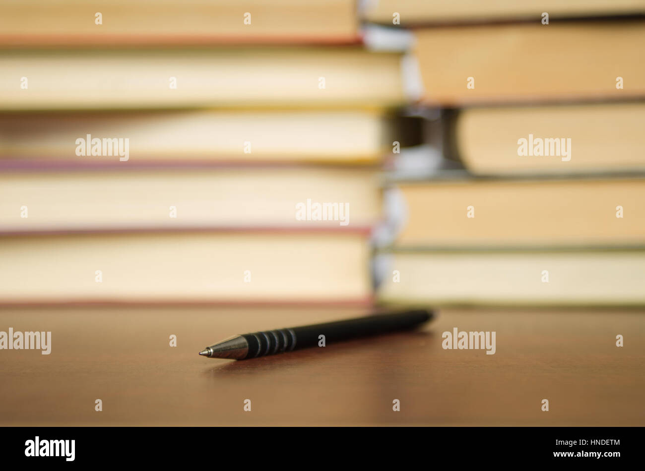 pen on background of a stack of colorful books in a library or a room ...