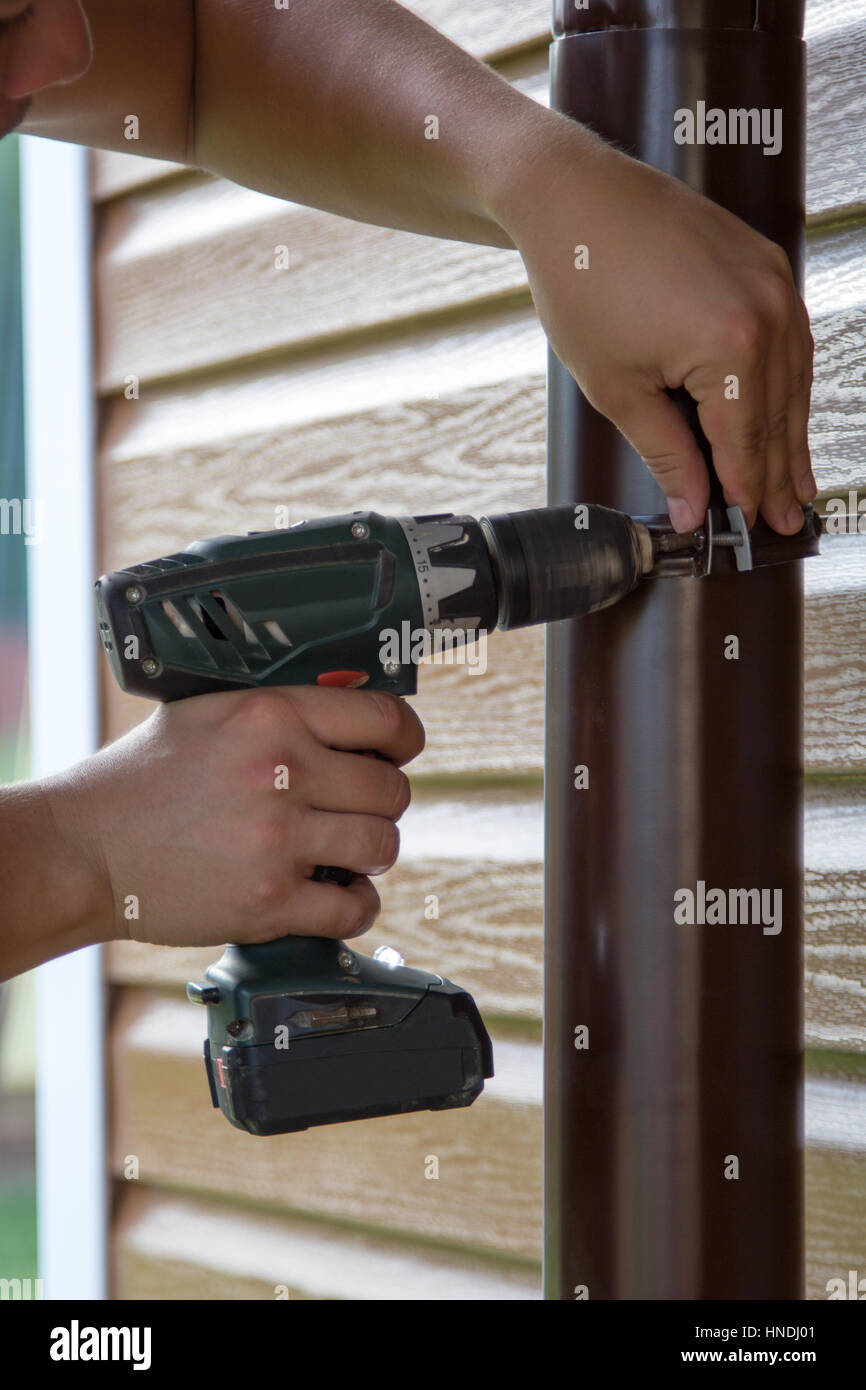 man fixes drain tube to wall with an electric screwdriver Stock Photo ...