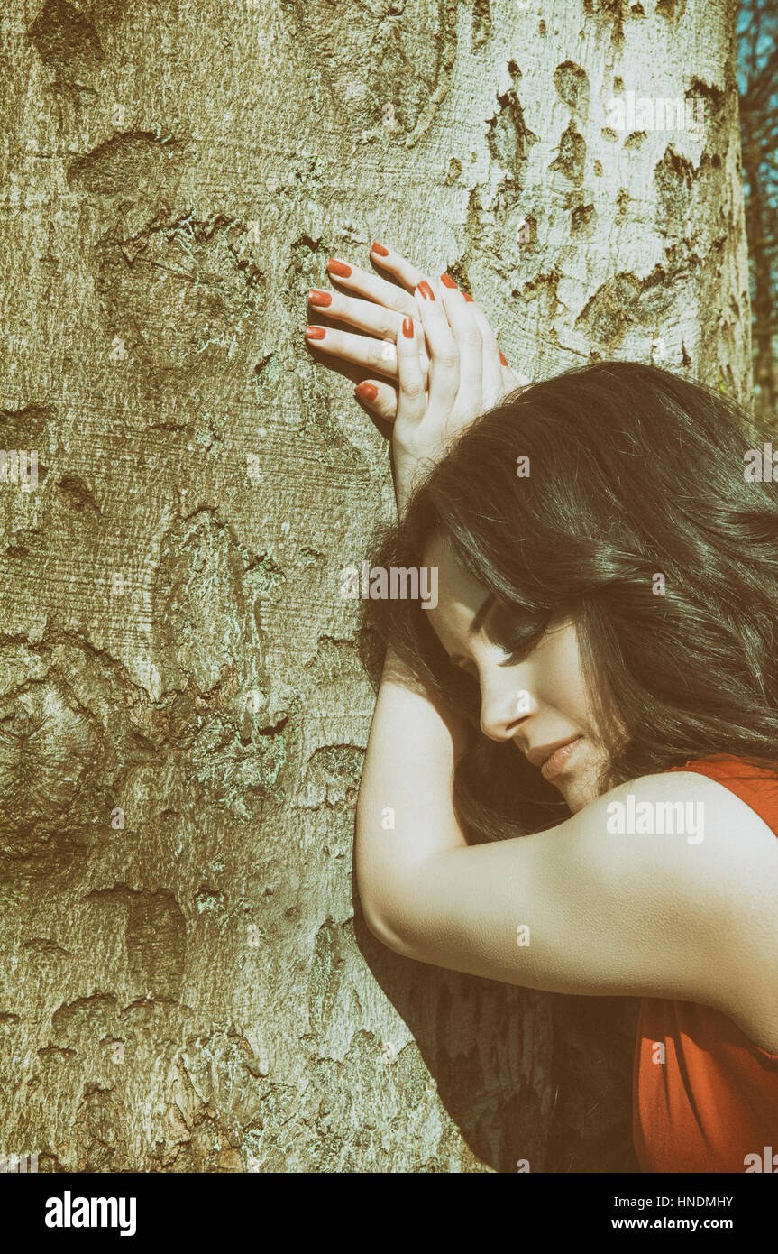 Sad woman leaning against the tree outdoors Stock Photo - Alamy