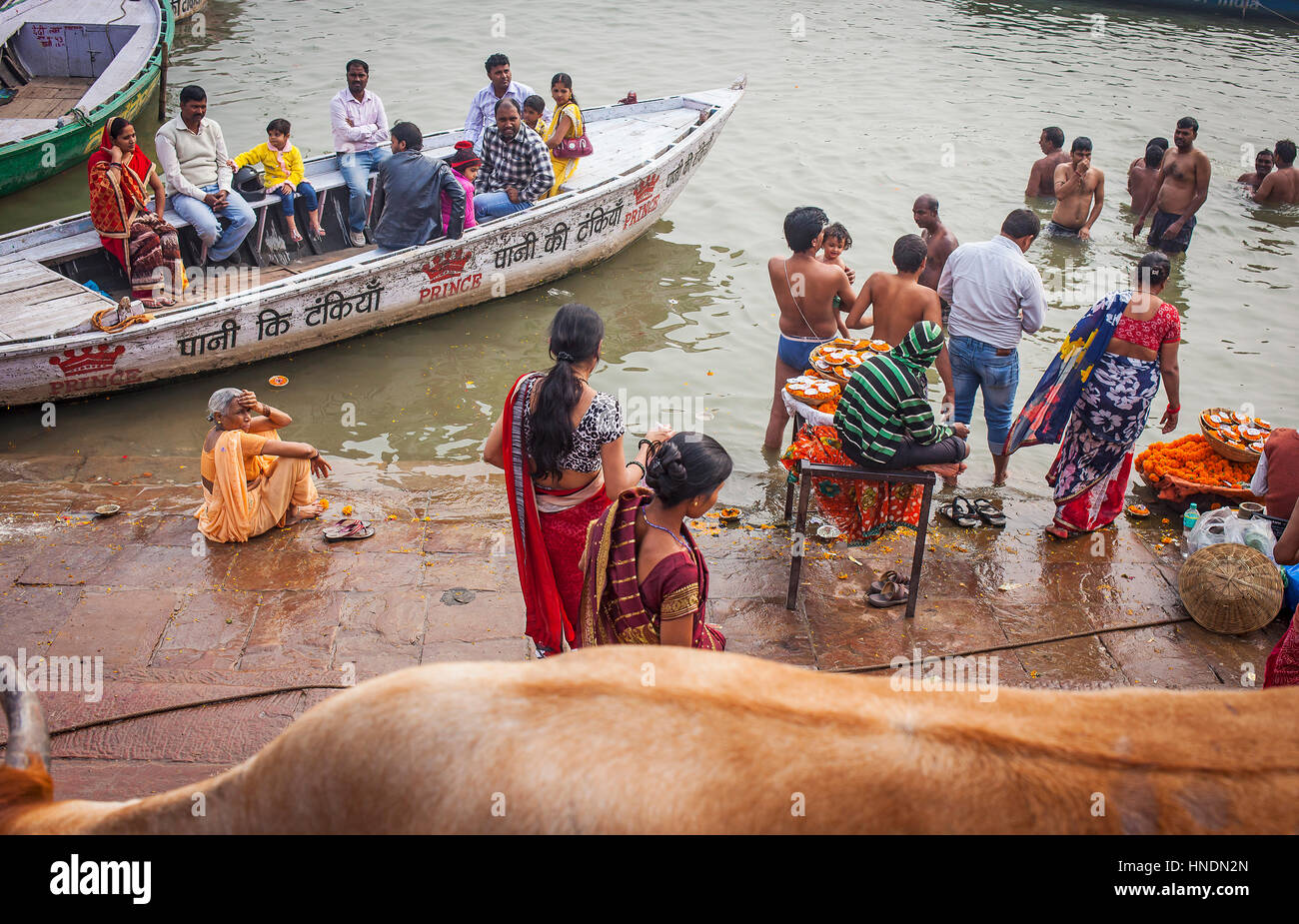 women and men praying and bathing, in the ghats of Ganges river ...
