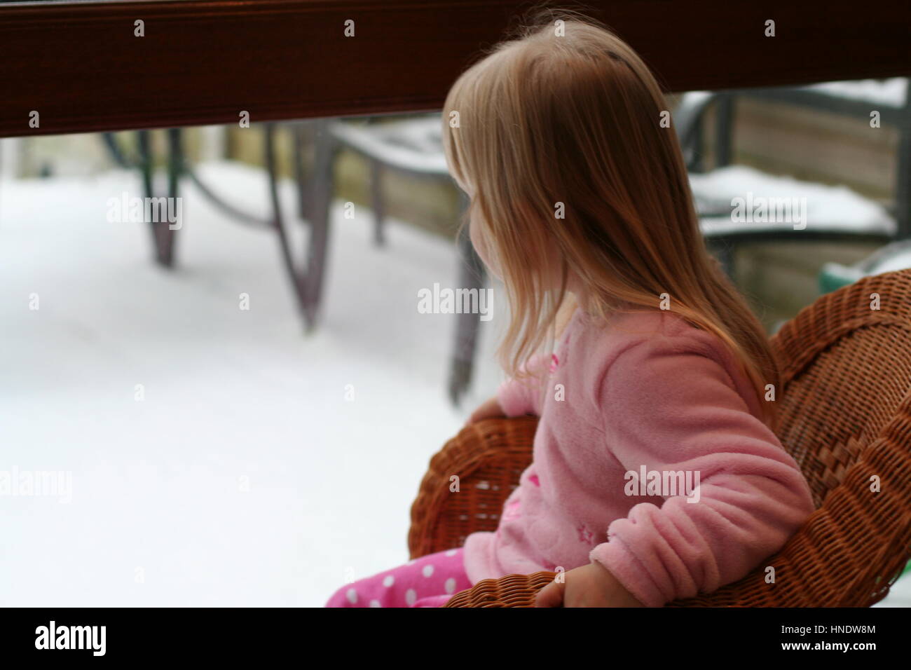 Sweet blonde girl child kid toddler looking out the window snow falling ...