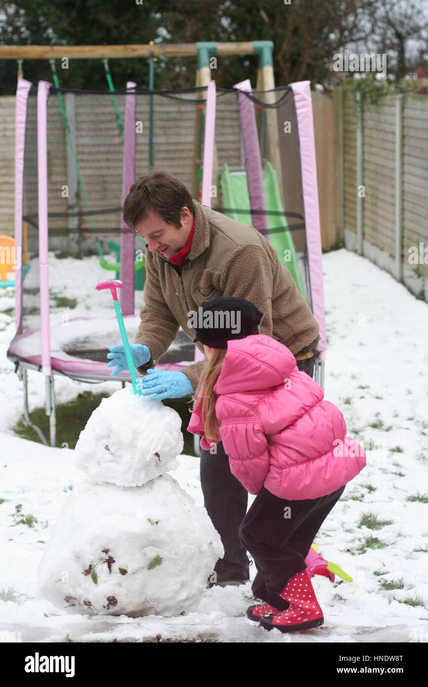Little girl child kid making a snowman with her Daddy dad father ...