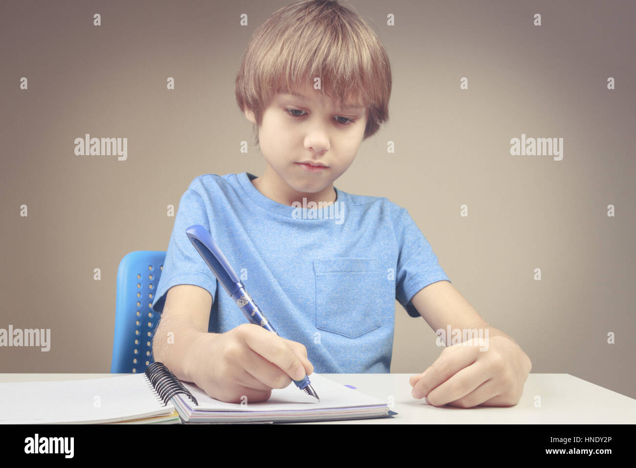 Boy using pen and writing on spiral paper notebook. Boy doing his ...
