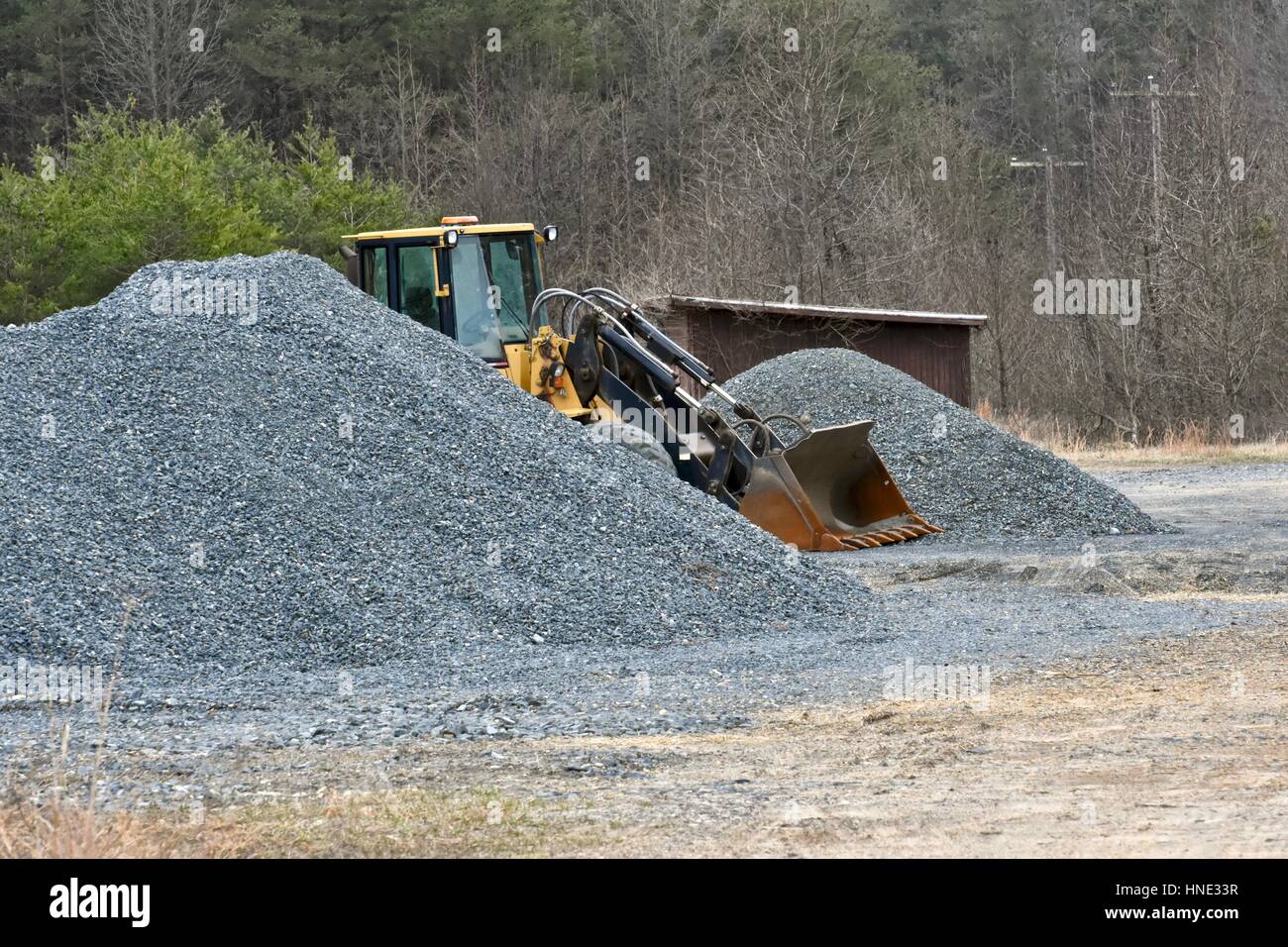 Back hoe parked in between two piles of gravel Stock Photo - Alamy