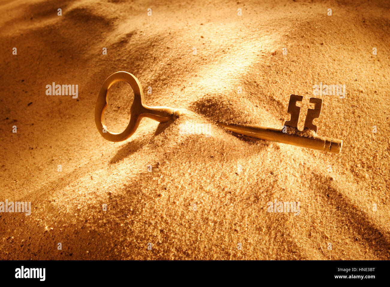 Golden Key in Sand Stock Photo - Alamy