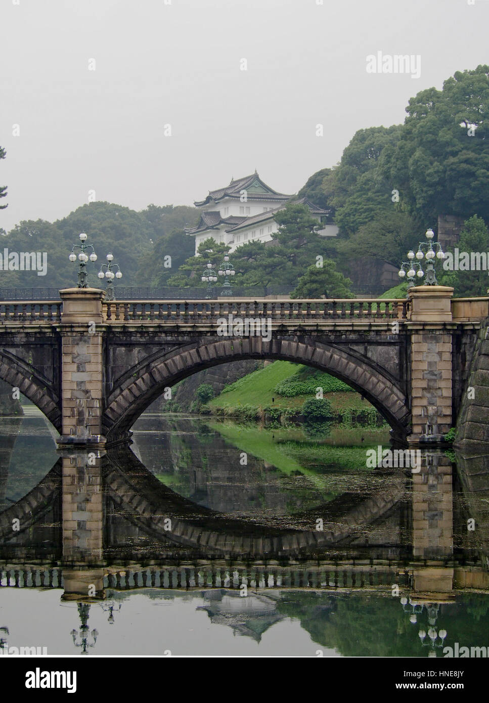 A traditional stone bridge reflects in the still water in front of the ...