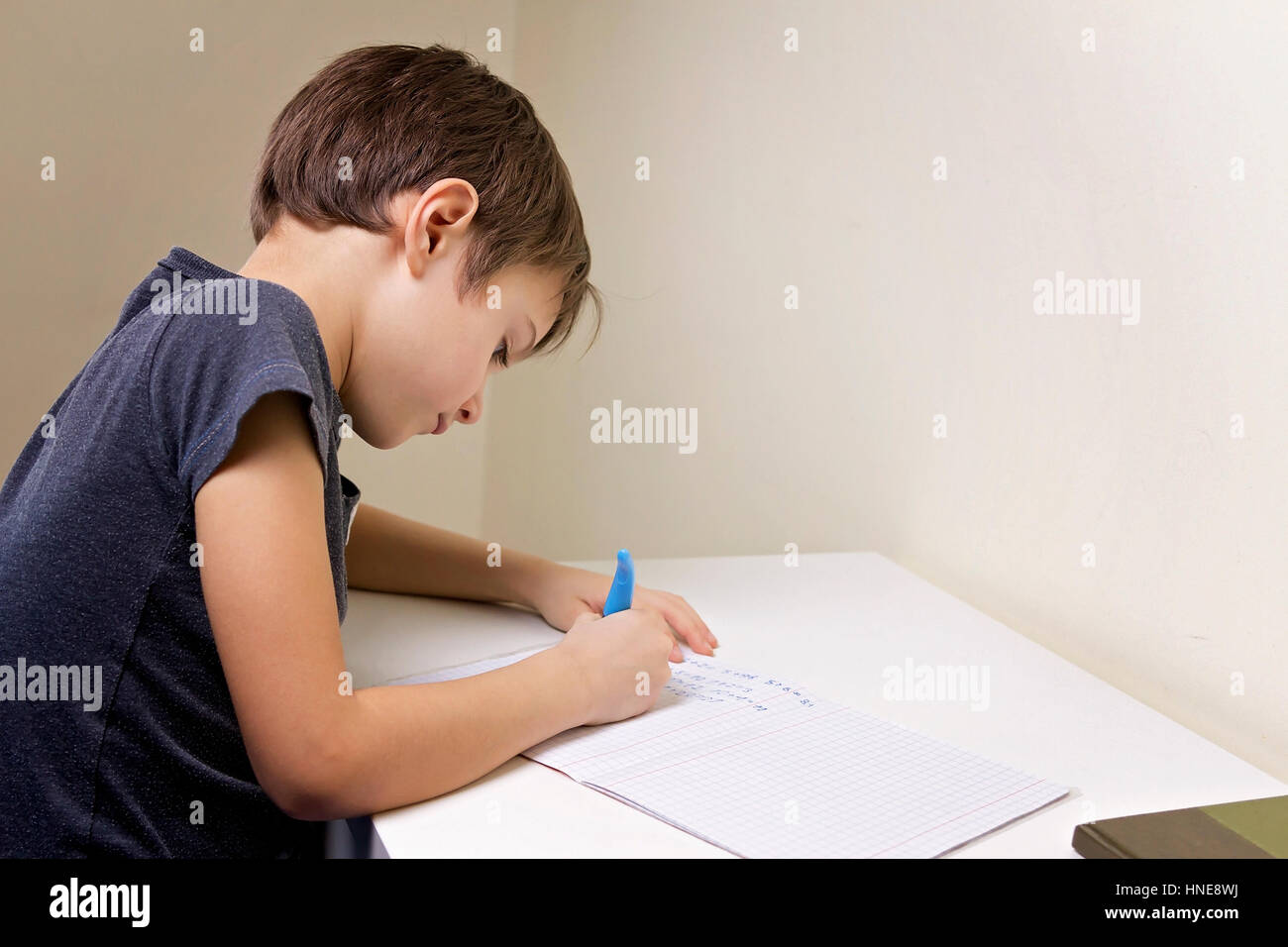 Boy writing at the desk at home. Child doing his homework. School ...