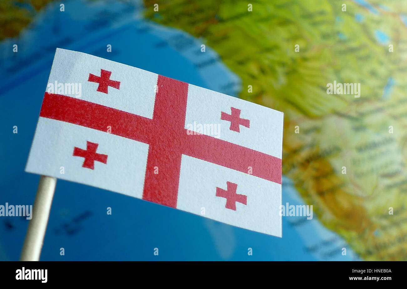 Georgian flag with a globe map as a background macro Stock Photo - Alamy