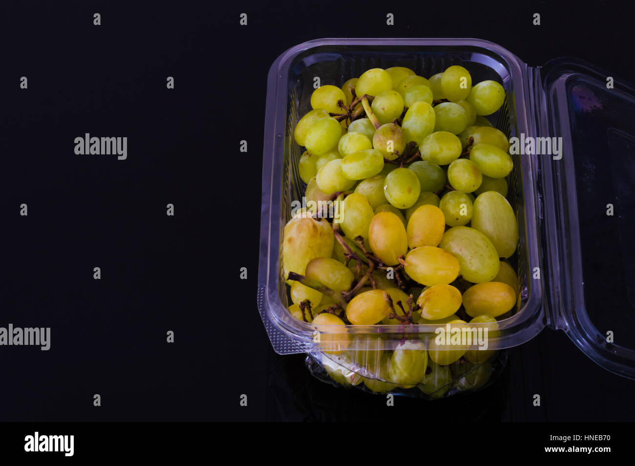 Bunch of fresh grapes in plastic cup on black background Stock Photo ...