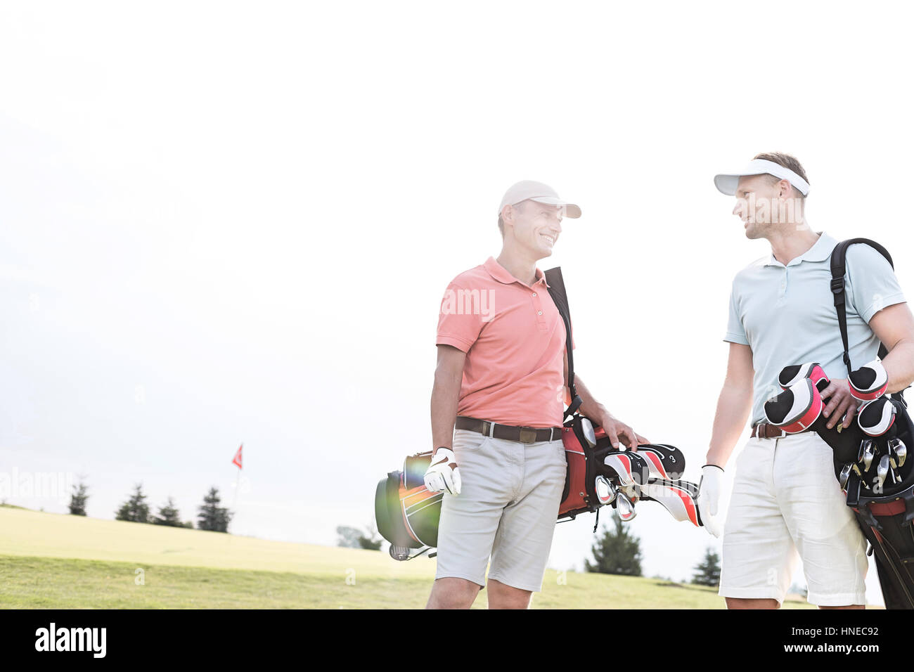 Smiling men talking at golf course against clear sky Stock Photo - Alamy