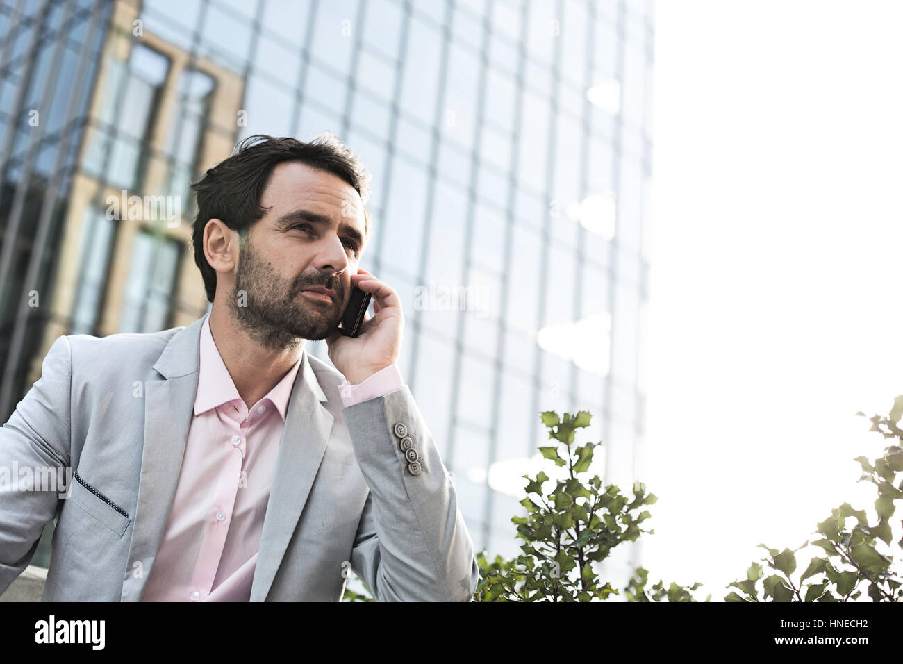Businessman answering mobile phone outside office building Stock Photo ...