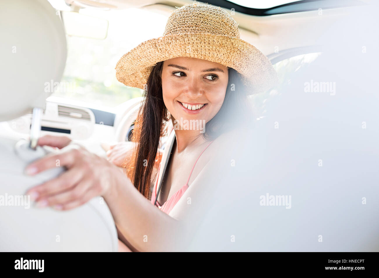 Happy woman looking back while driving car Stock Photo - Alamy
