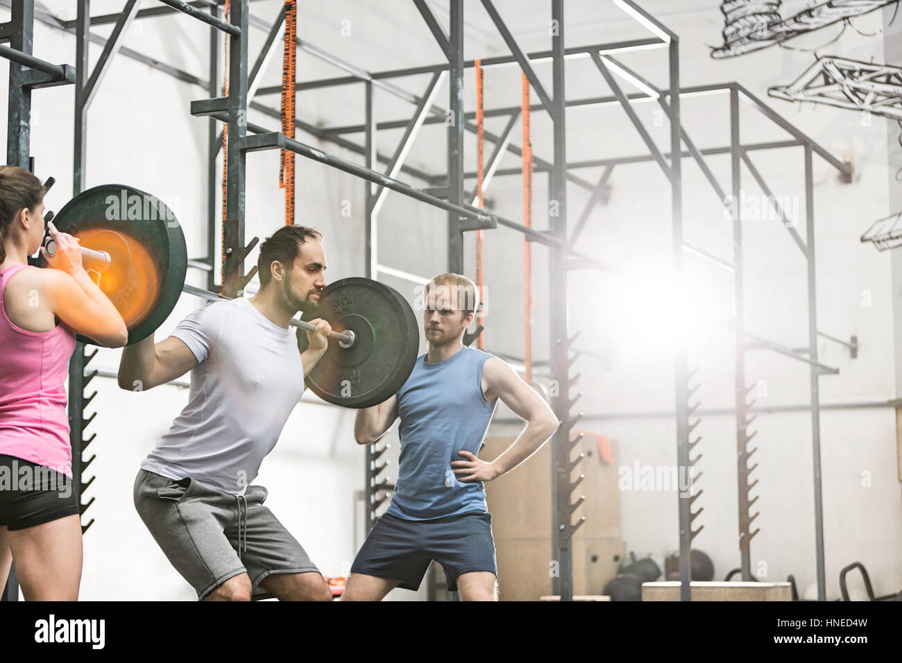 People assisting man in lifting barbell at crossfit gym Stock Photo - Alamy