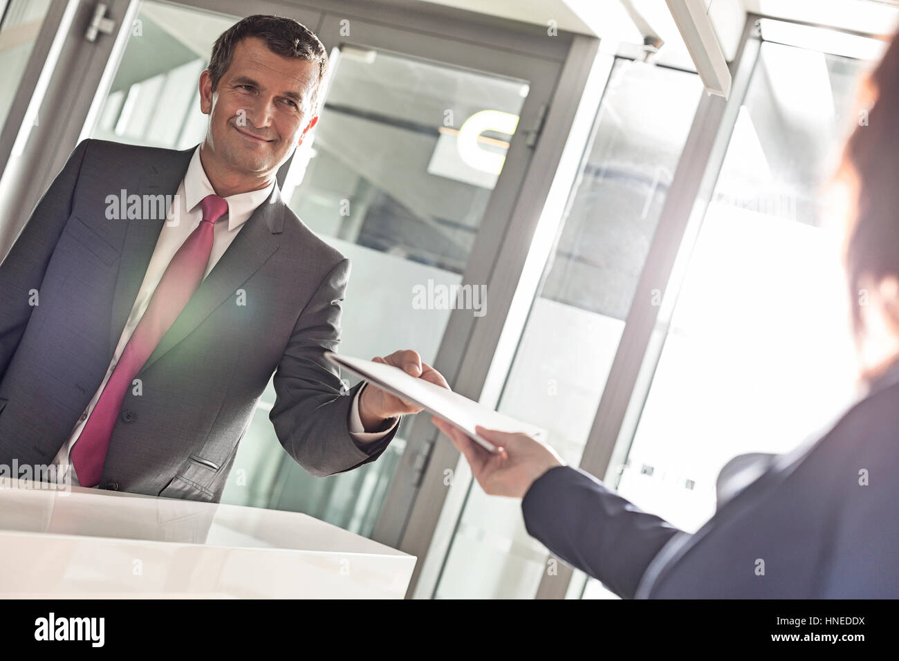 Businessman receiving document from receptionist in office Stock Photo ...