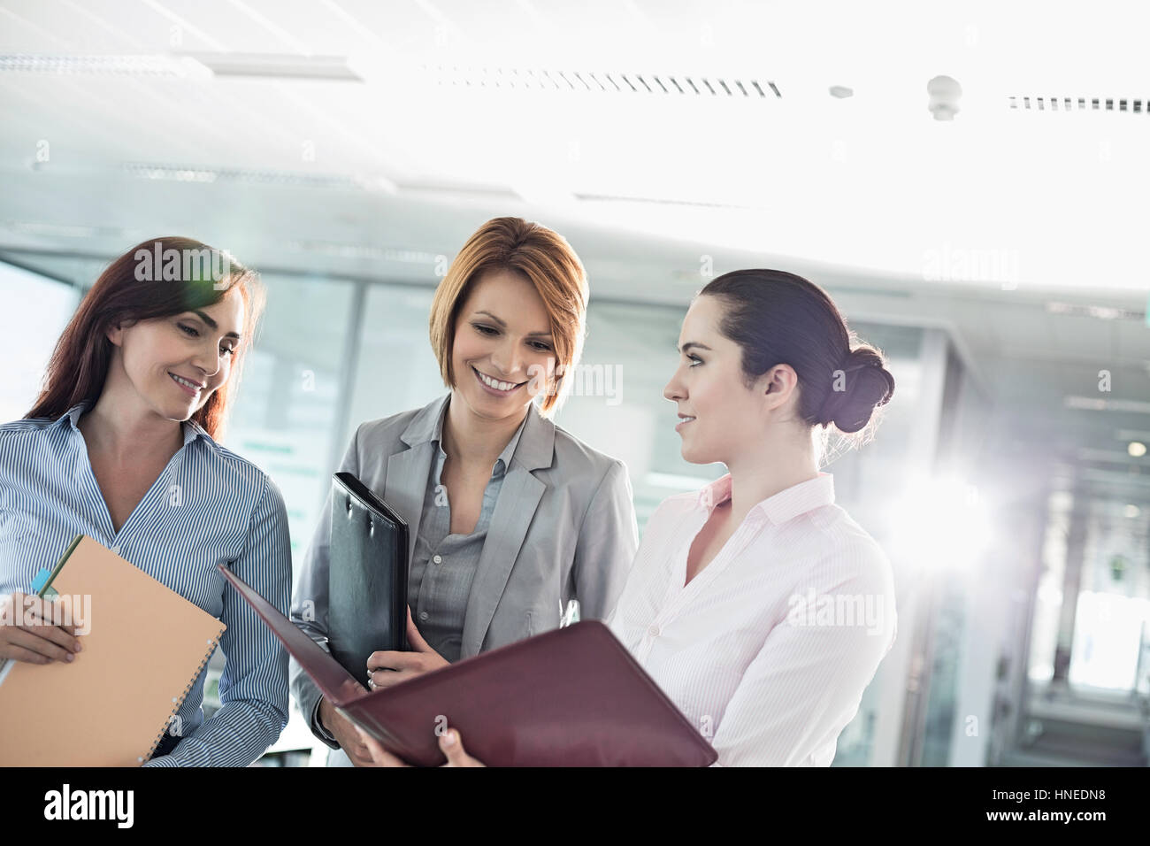 Businesswomen with file folders discussing in office Stock Photo - Alamy