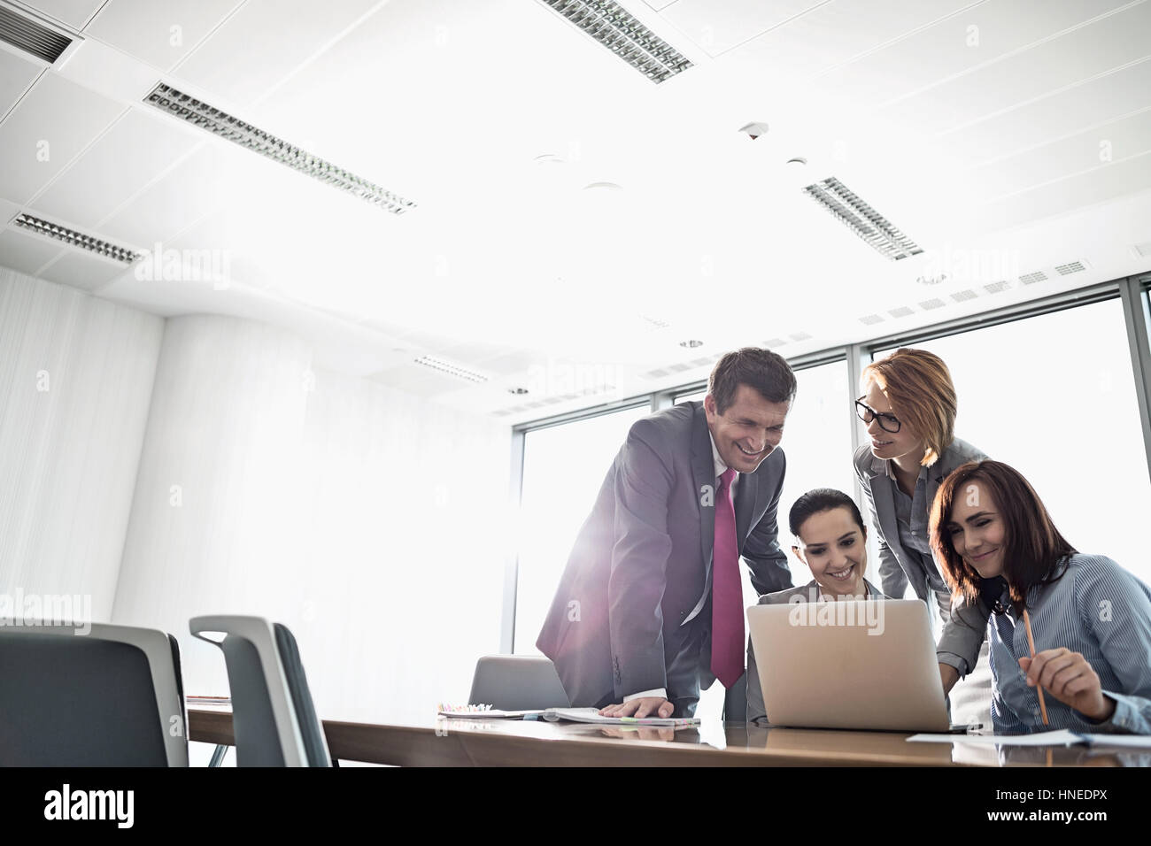 Businesspeople using laptop at conference table Stock Photo - Alamy