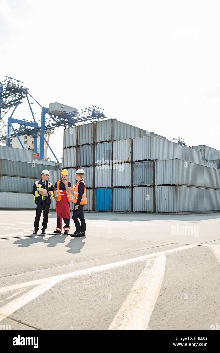Full-length of workers talking in shipping yard Stock Photo - Alamy